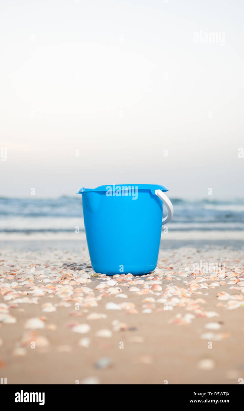 Blue bucket standing on sand at the beach at sunset Stock Photo - Alamy