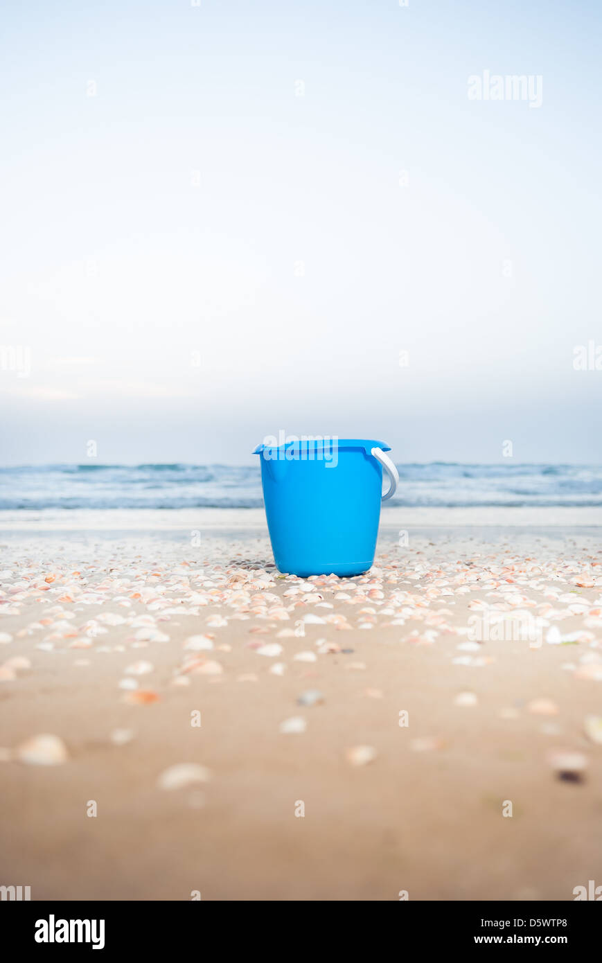 Blue bucket standing on sand at the beach at sunset Stock Photo - Alamy