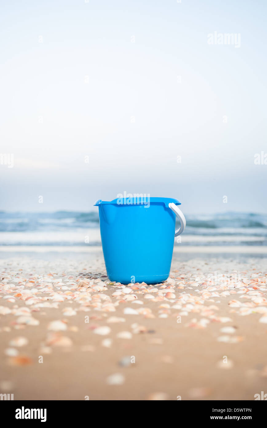 Blue bucket standing on sand at the beach at sunset Stock Photo - Alamy