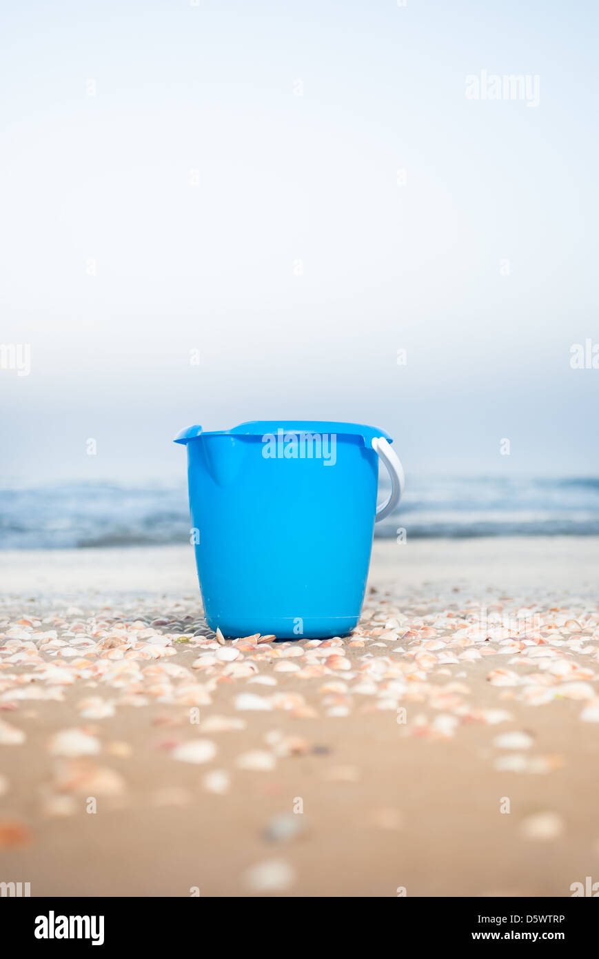 Blue bucket standing on sand at the beach at sunset Stock Photo - Alamy