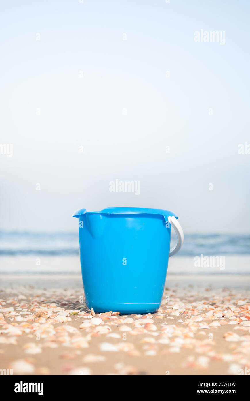 Blue bucket standing on sand at the beach at sunset Stock Photo - Alamy