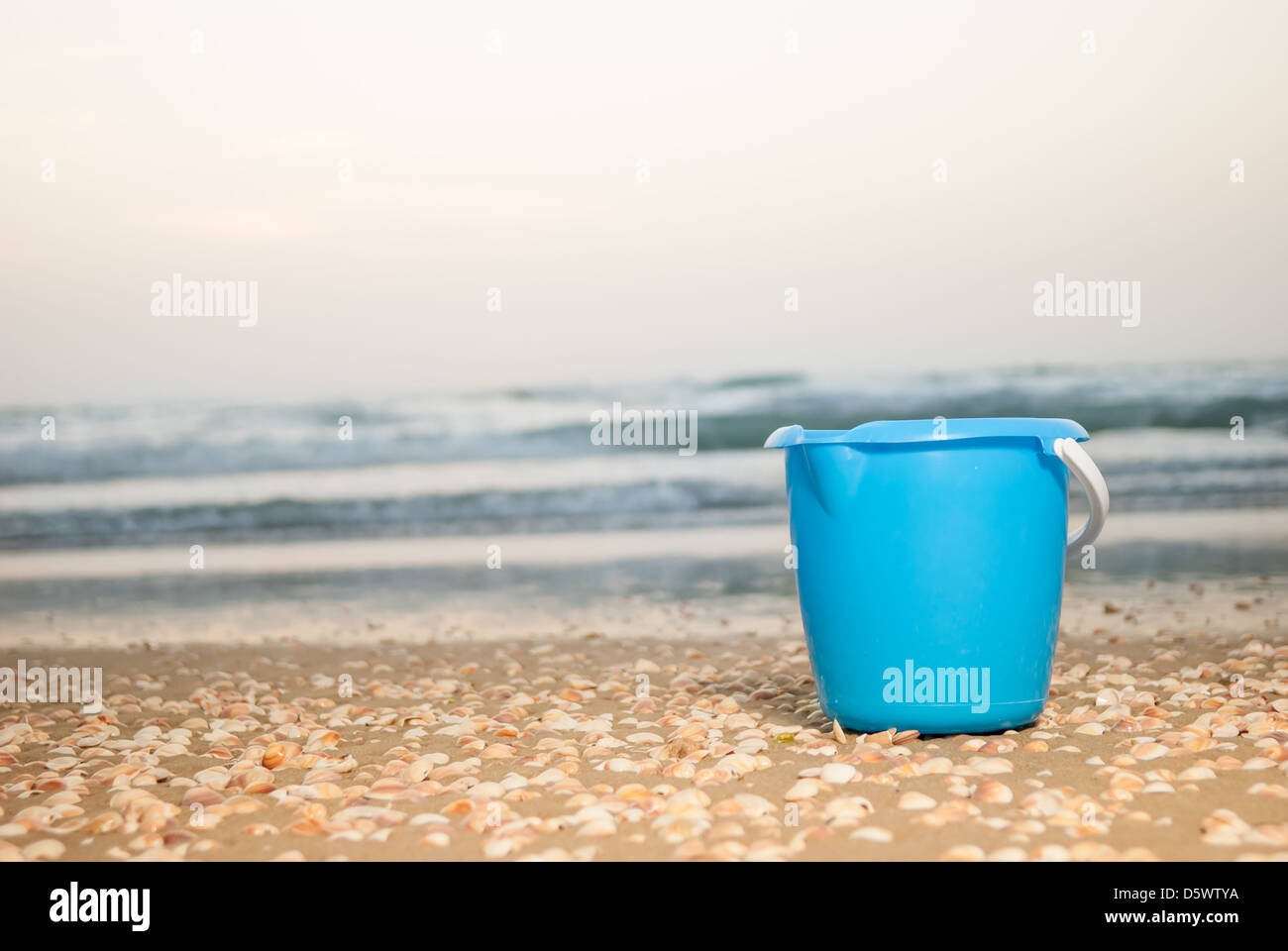 Blue bucket standing on sand at the beach at sunset Stock Photo - Alamy