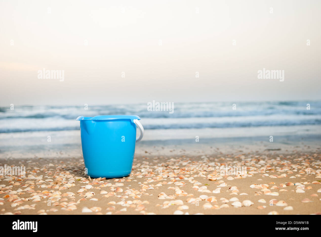 Blue bucket standing on sand at the beach at sunset Stock Photo - Alamy