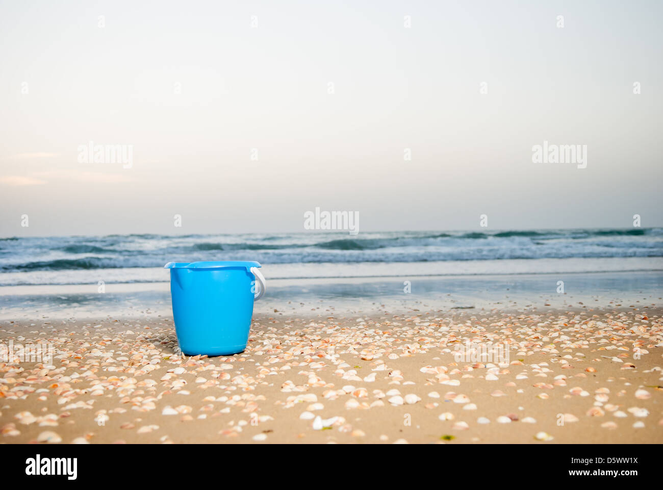 Blue bucket standing on sand at the beach at sunset Stock Photo - Alamy