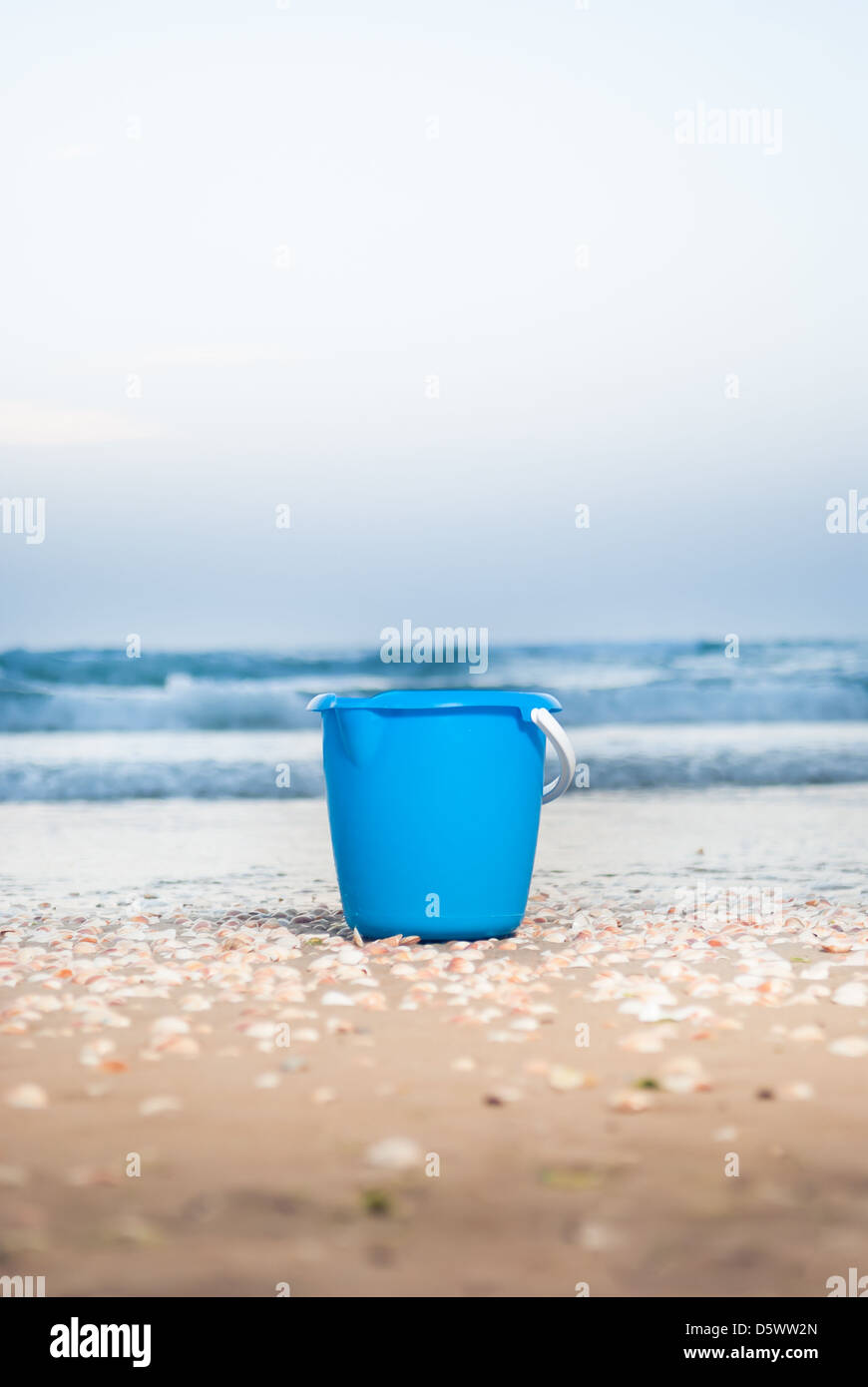 Blue bucket standing on sand at the beach at sunset Stock Photo - Alamy