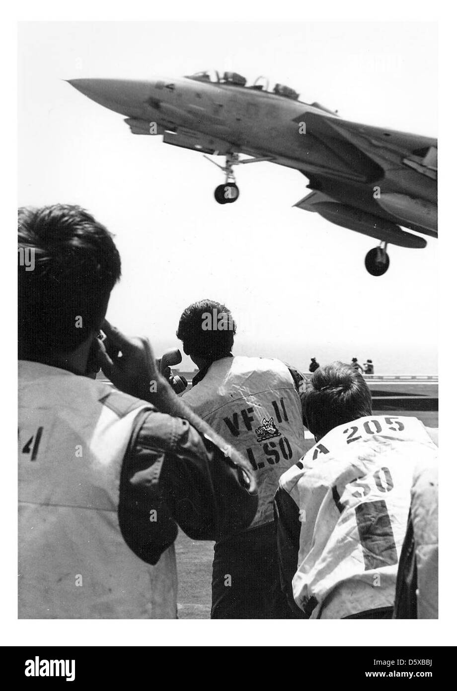 Landing Signal Officers (LSOs) observe a Grumman F-14 Tomcat from ...