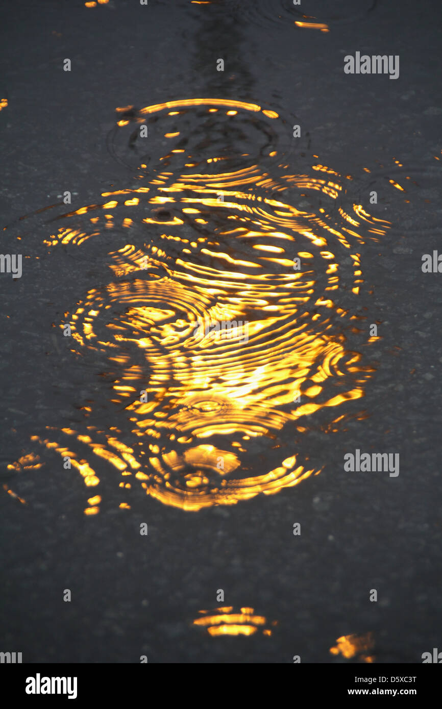 rain drops in puddle with street light reflection Stock Photo - Alamy