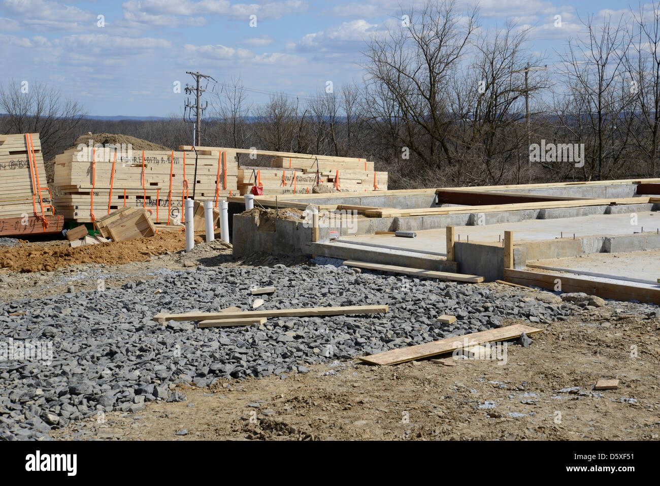 Piles of new lumber by a cement foundation for a new home construction ...