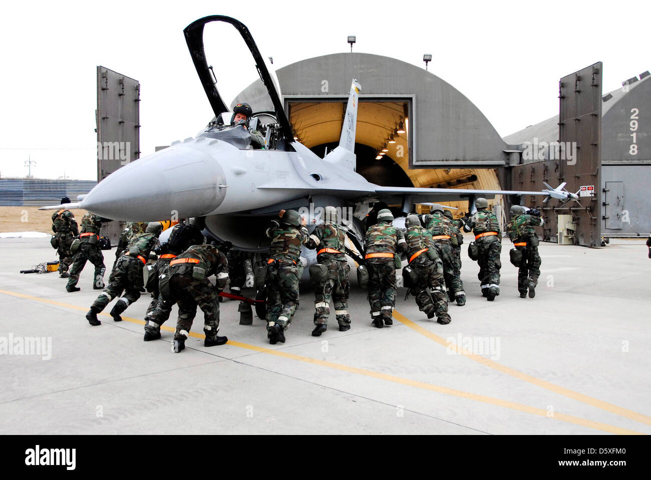 Airmen from the 79th Fighter Squadron push an F-16 Fighting Falcon into ...