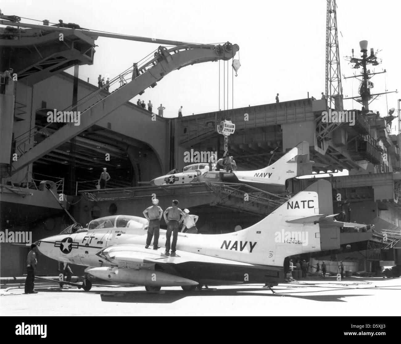 Grumman F9F-8T "Cougar" being hoisted aboard a aircraft carrier Stock ...