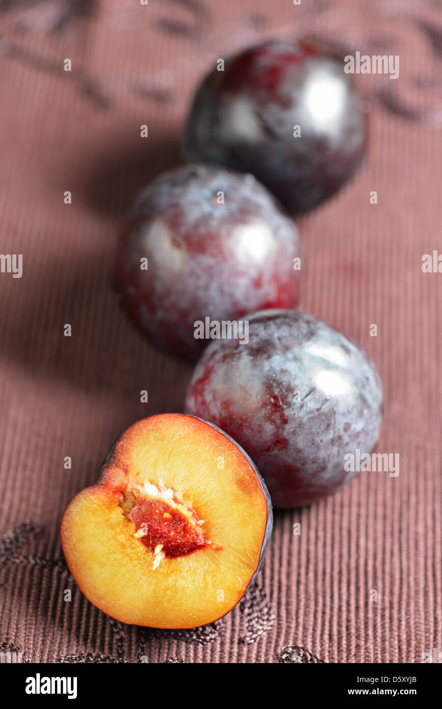 4 plums on table cloth close up Stock Photo - Alamy