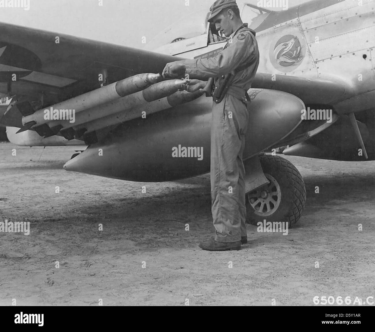An armorer attaches rockets to the wing of a North American P-51 ...