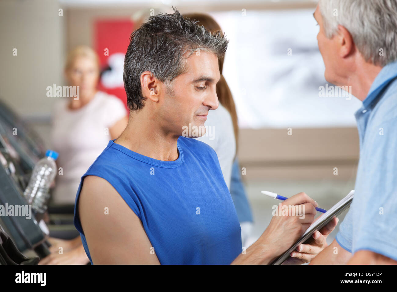 Fitness trainer coaching senior on treadmill in gym Stock Photo - Alamy