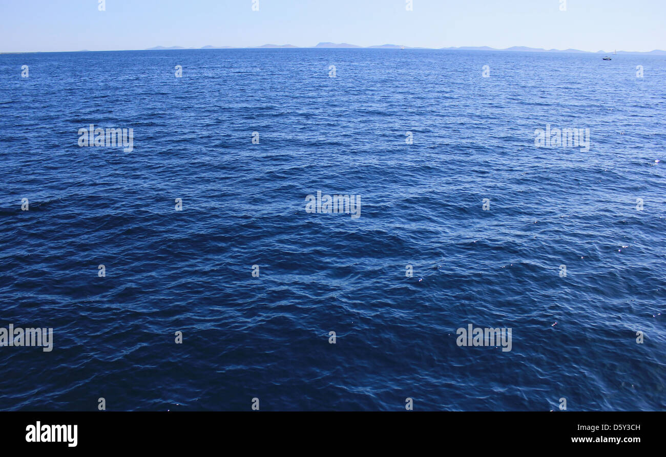 Open blue sea and land on the horizon Stock Photo - Alamy