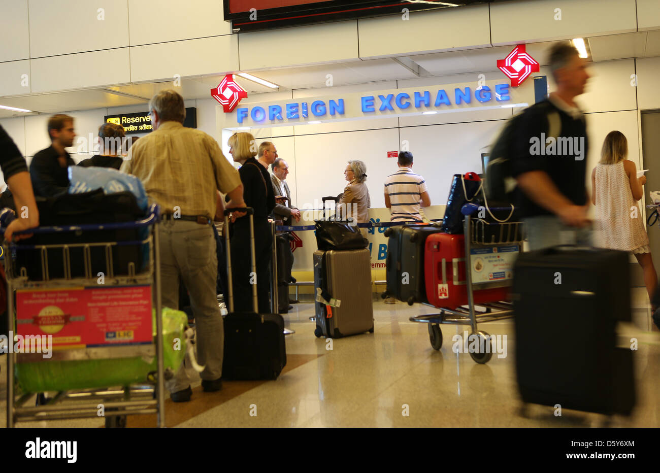 Passengers queue up in front of the exchange counter at the arrival ...