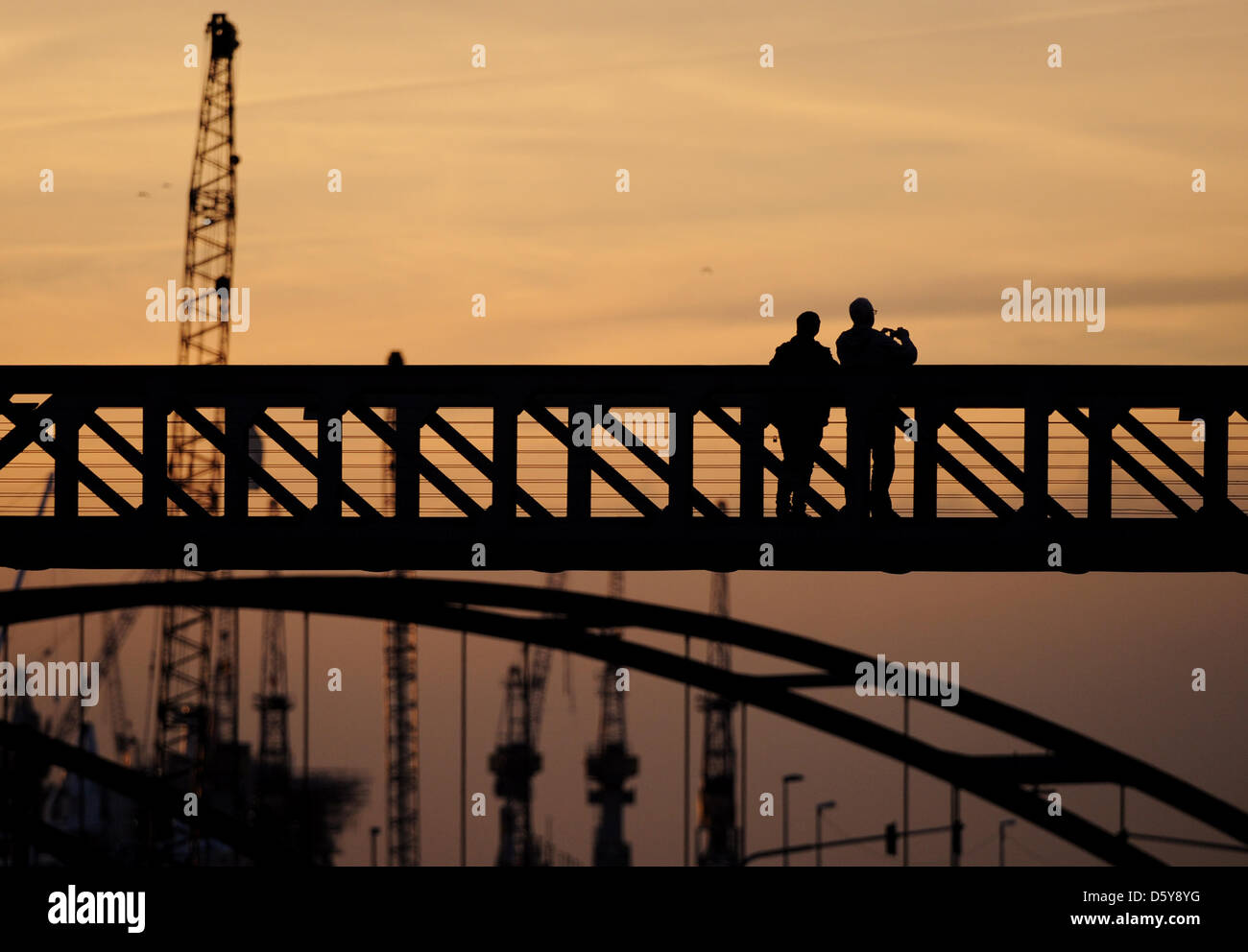 Pedestrians stand on a pedestrian bridge in the warehouse district in ...