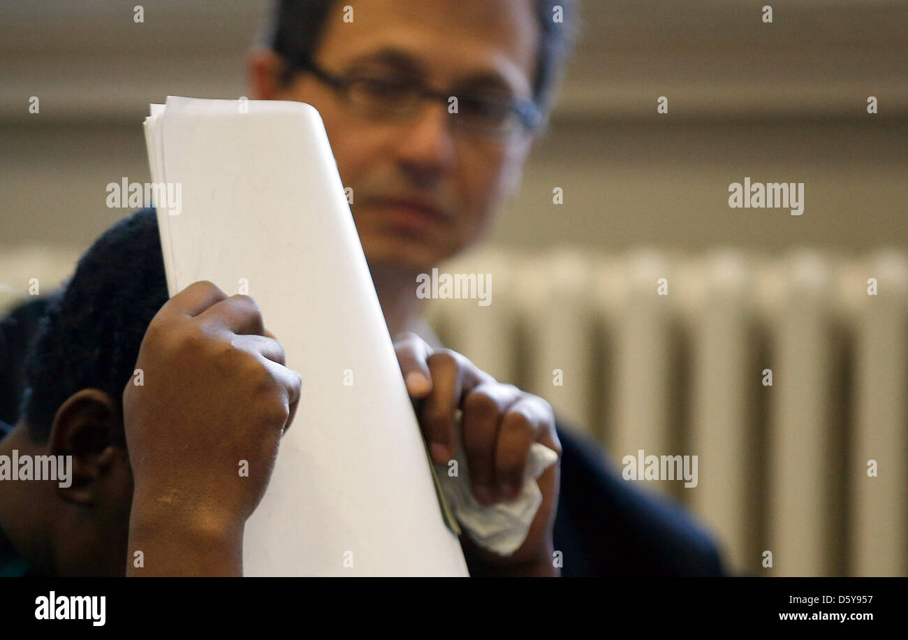 One of the defendants (L) covers his face with a binder next to his ...