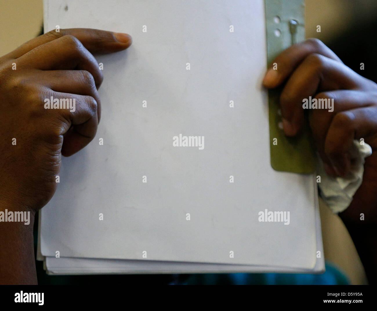 One of the defendants covers his face with a binder in the courtroom of ...