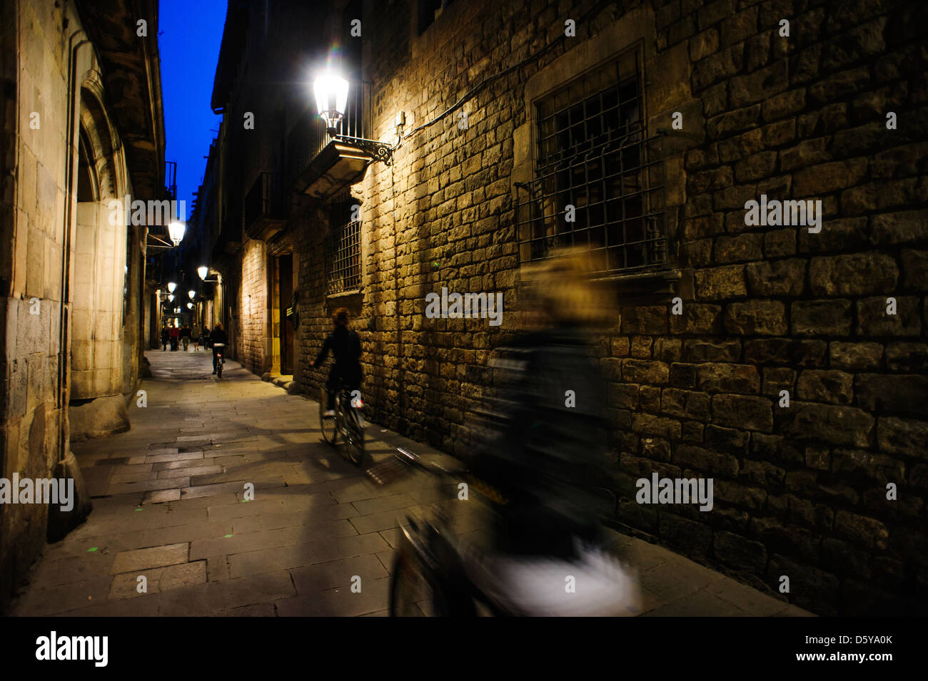People riding a bike in the gothic area of Barcelona during the night ...