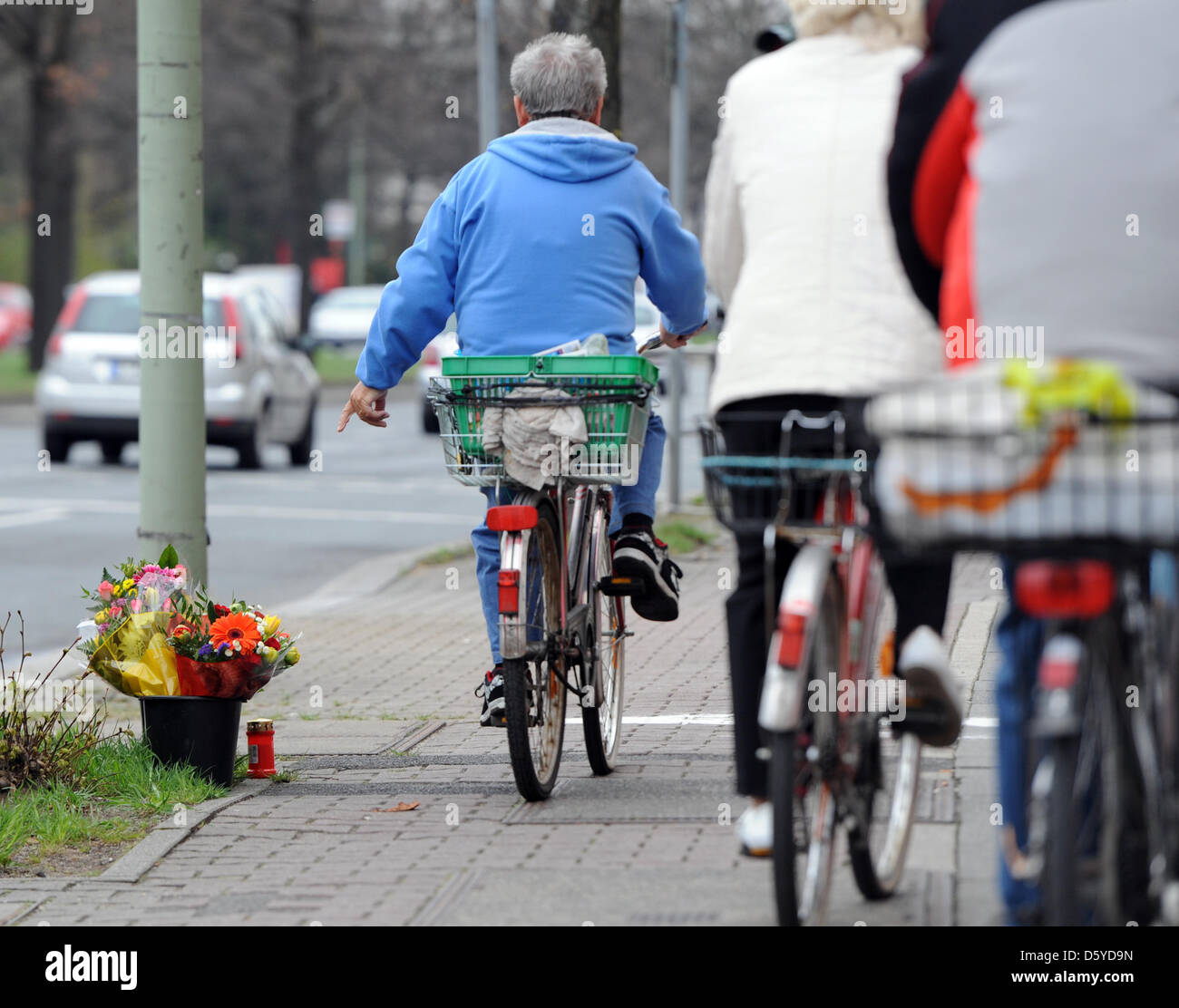 A group of cyclers drives past the spot where flowers and candles mark ...