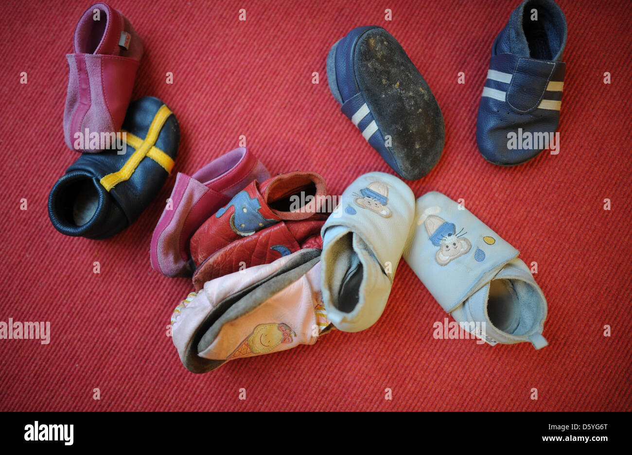 Pairs of childrens' shoes and slippers lie on the floor of a nursery ...