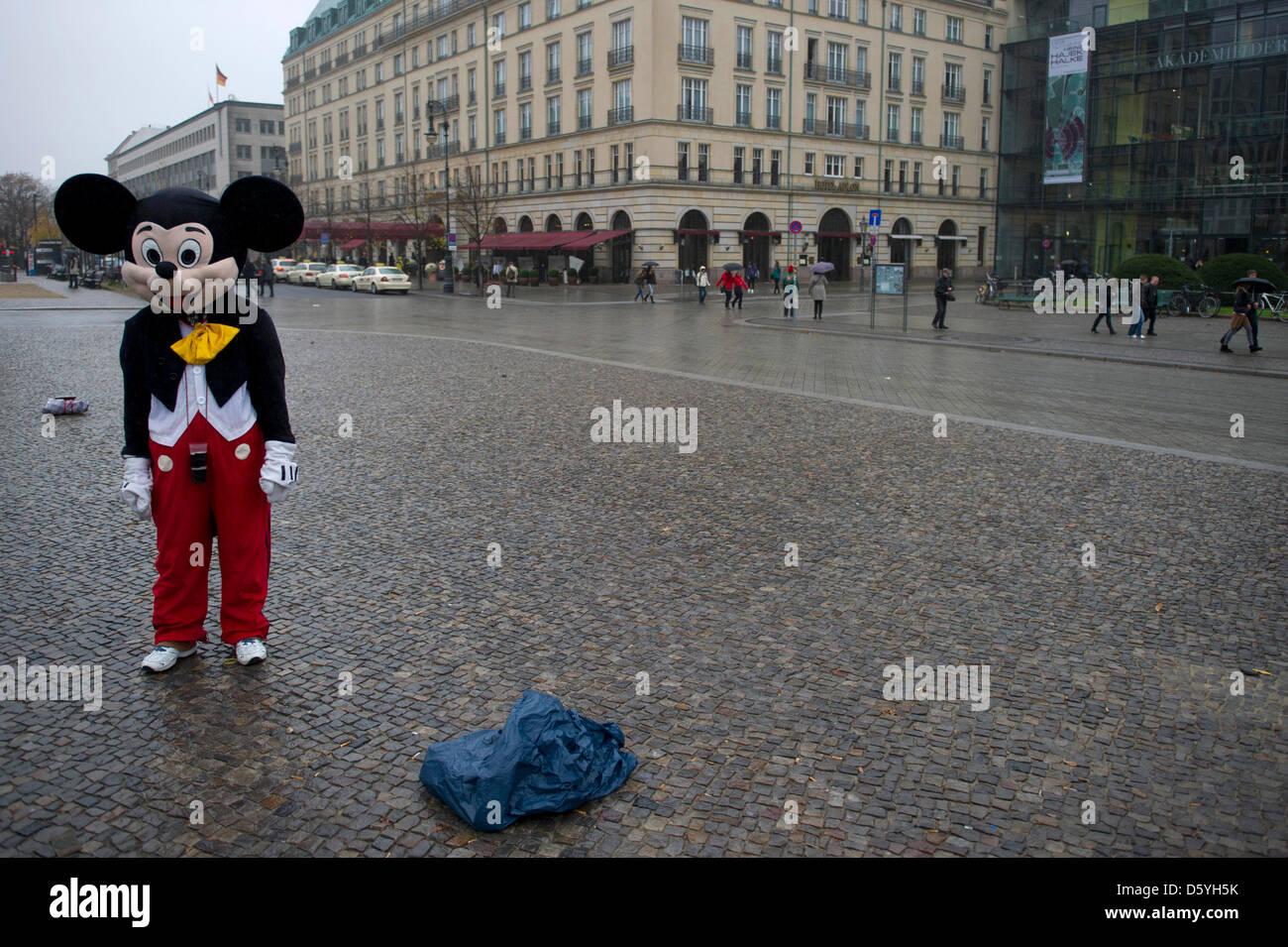 A person dressed as Micky Mouse stands during a rain shower on Pariser ...