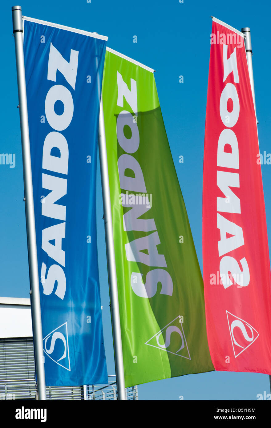 Three colorful flag with "Sandoz" written on them wave in front of a ...