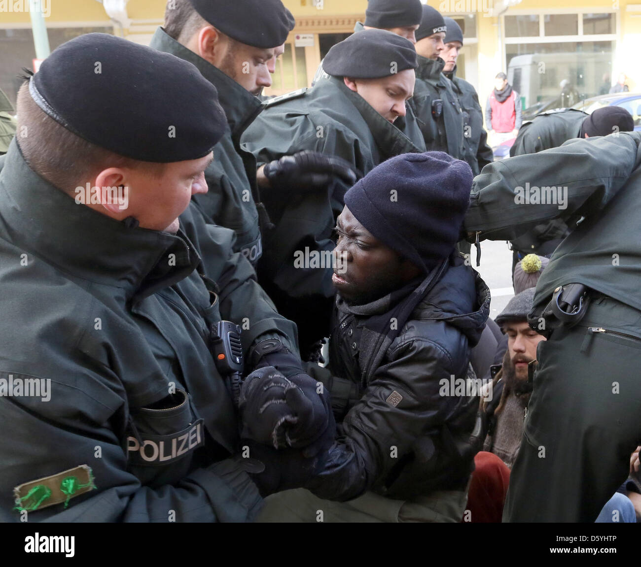 Police officers break up a street blockade of refugees and ...