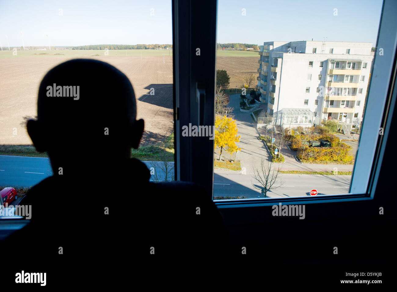 An asylum seeker looks out of the window of a housing facility for ...