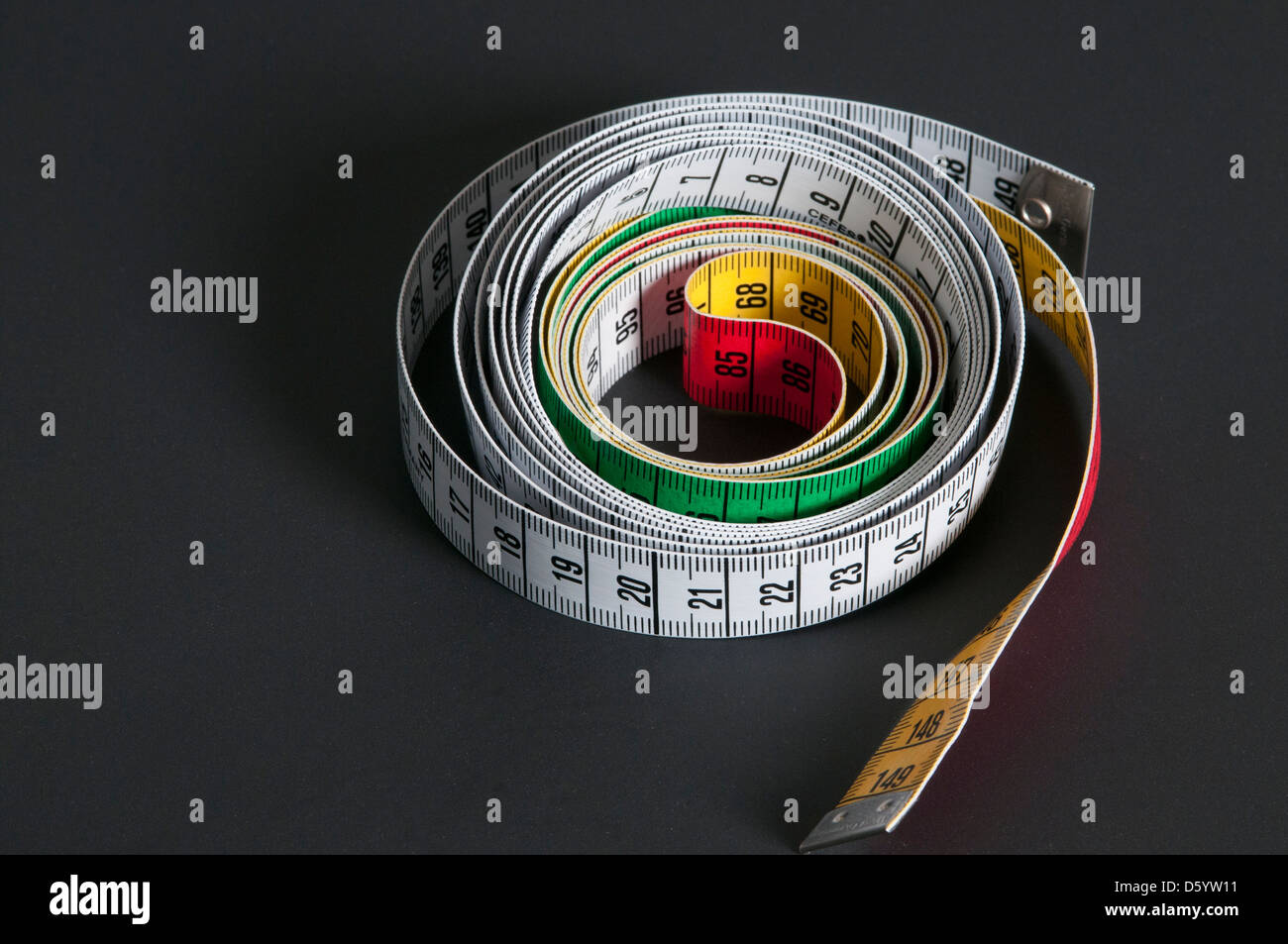 rolled measuring tape on dark grey background Stock Photo - Alamy