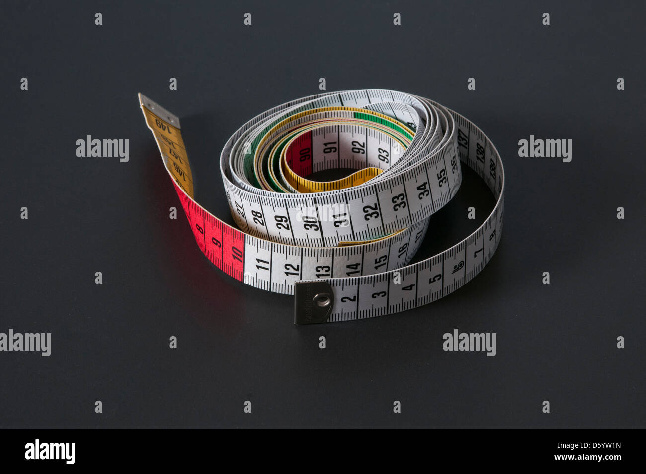 rolled measuring tape on dark grey background Stock Photo - Alamy