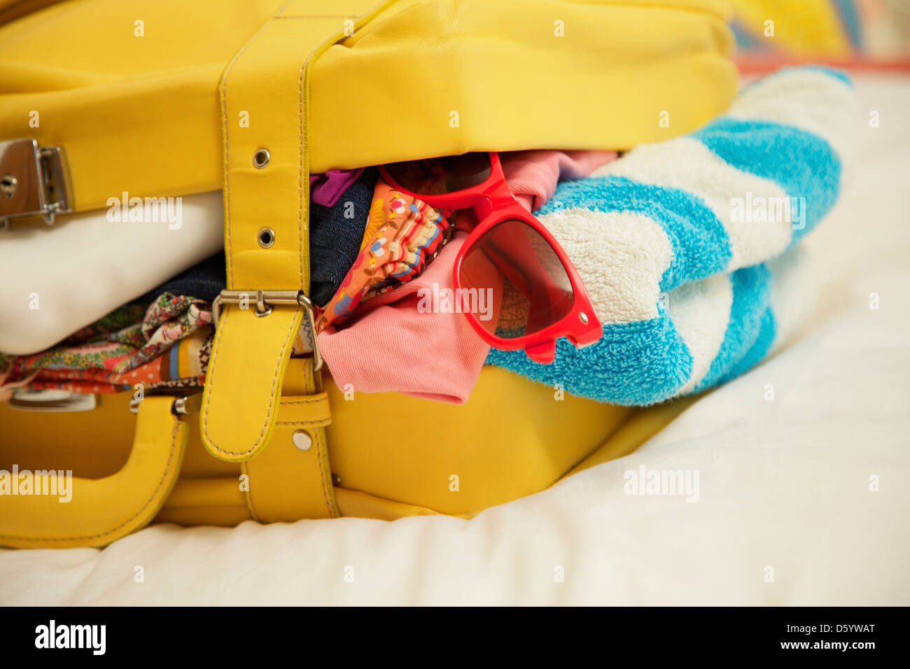 Yellow Suitcase Bursting with Clothing Stock Photo - Alamy