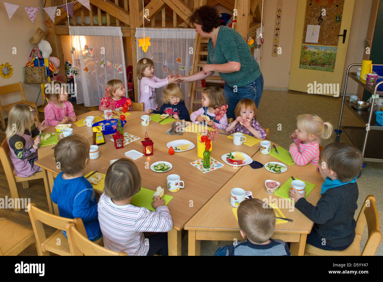 Daycare teacher Renate and pre-school children eat breakfast at ...