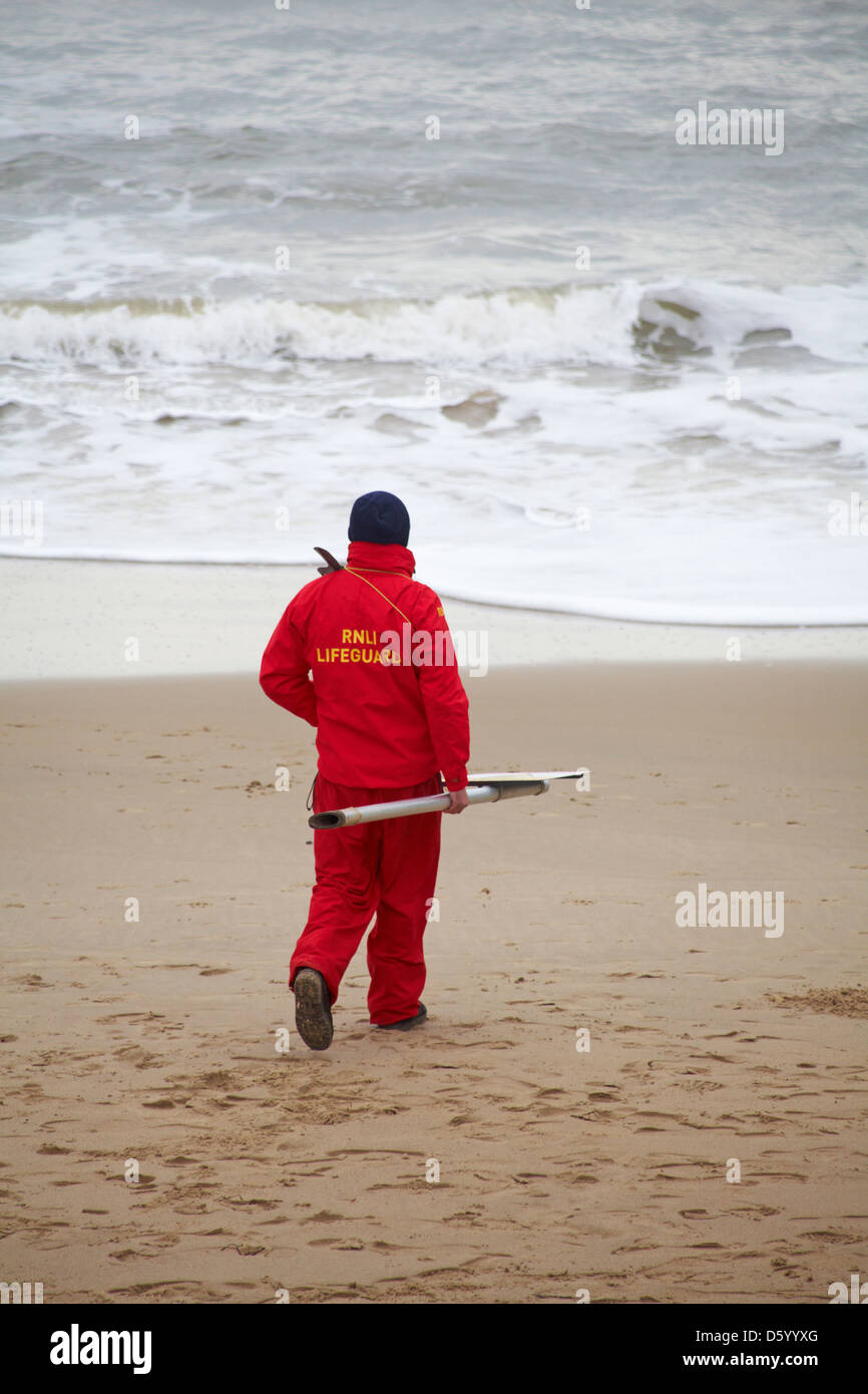 RNLI Lifeguard about to erect sign warning strong currents in this area ...