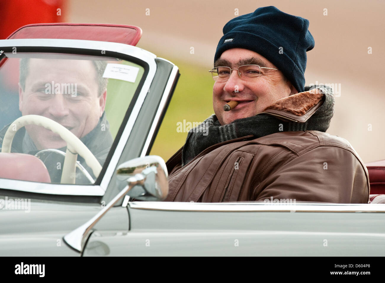 A rallye driver sits in an oldtimer smoking a cigar and waiting for the ...