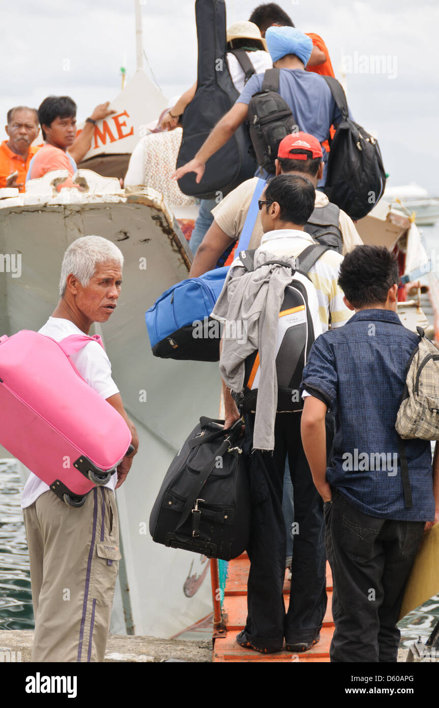 People, passengers, tourists boarding a small ferry ship, climbing a ...