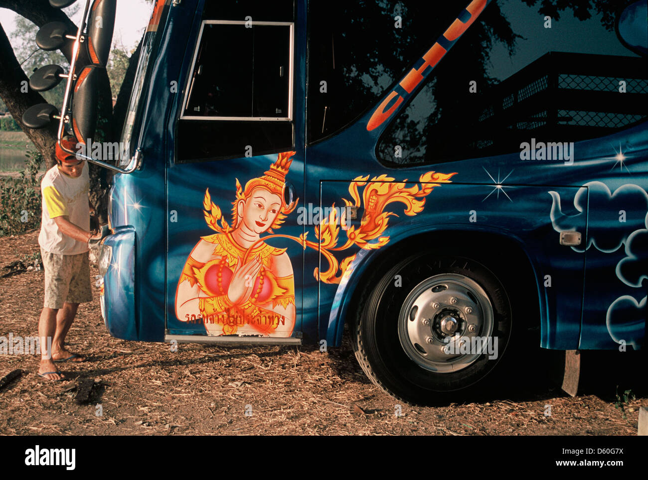 Helper washing a bus with a hindu deity painting on the door ( Thailand ...