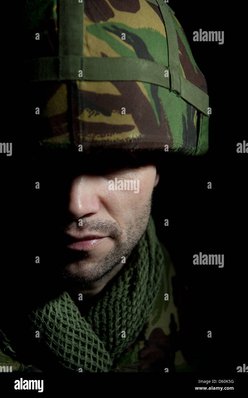Portrait of a British soldier in deep shadow against a black background ...