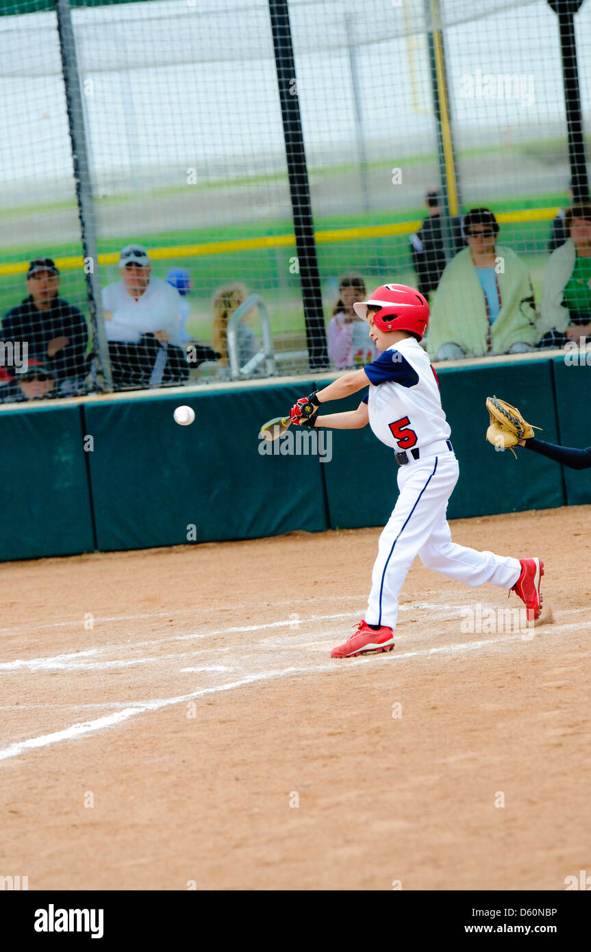 Little league baseball boy swinging the bat and about to hit the ball ...