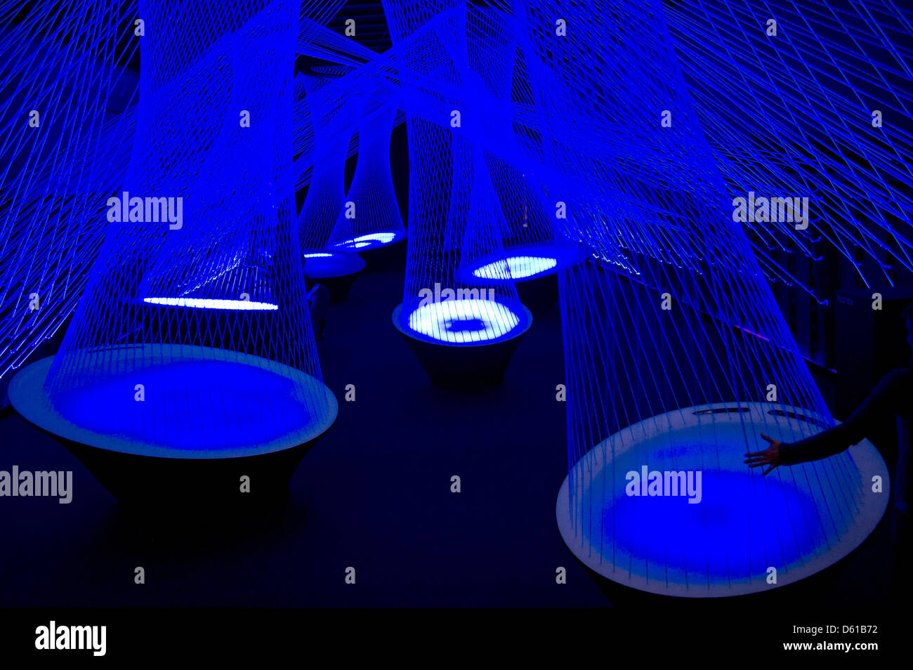 A student runs her hands over a net of glowing strings in the steel ...