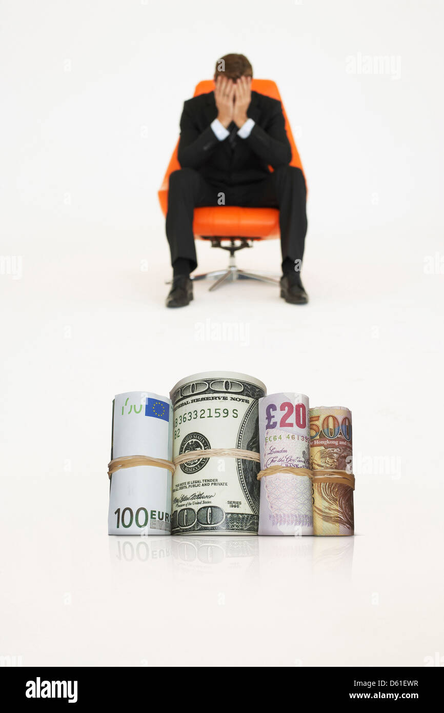 Money rolls with worried businessman chair representing financial ...