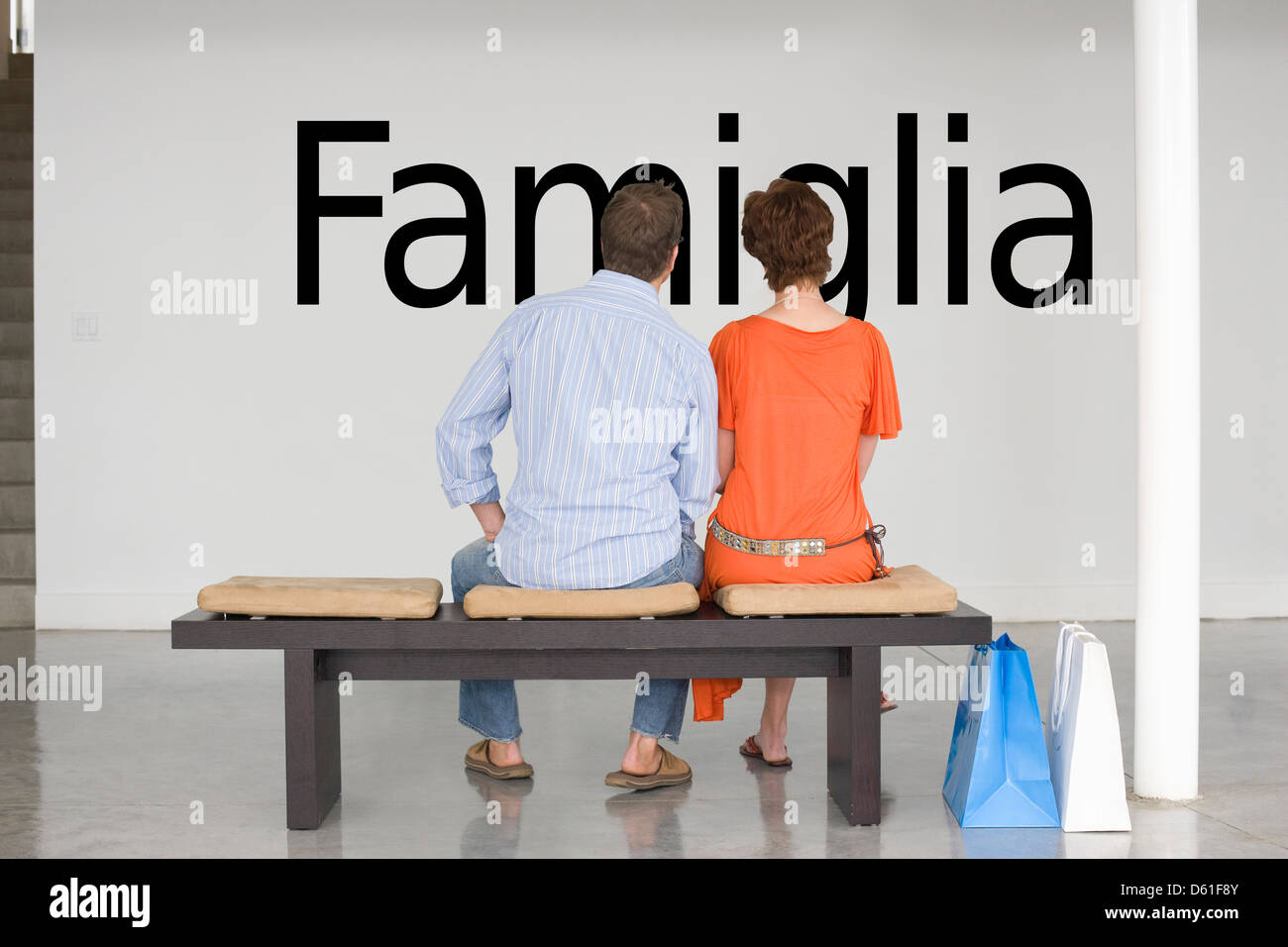 Rear view of couple seated bench reading Italian text "Famiglia ...