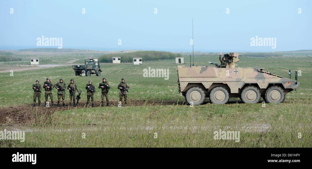 Soldiers stand next to an armoured fighting vehicle of the GTK Boxer ...