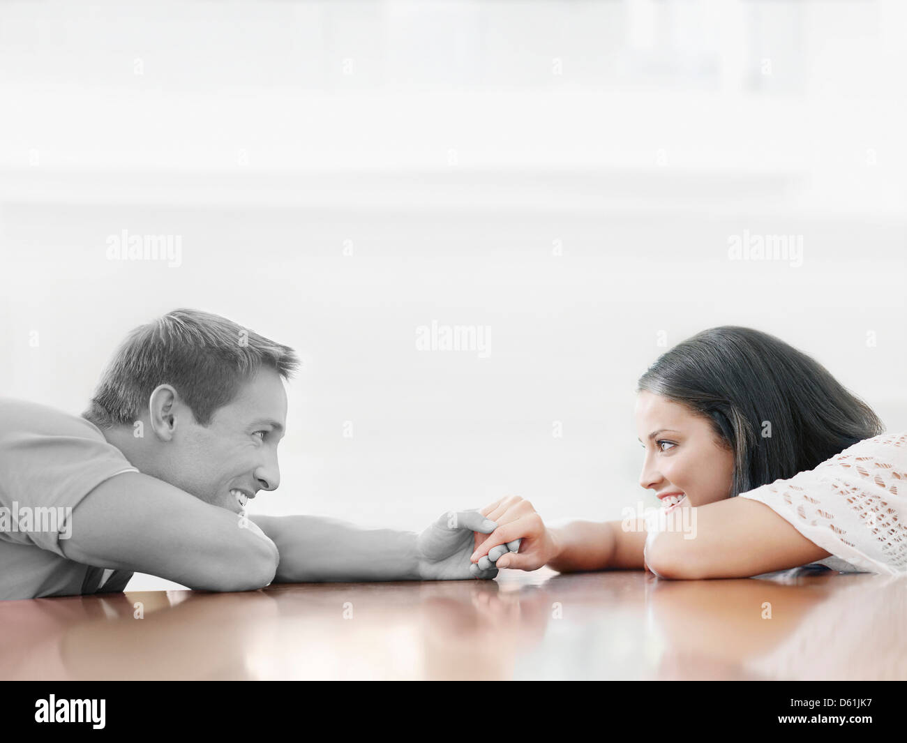 Affectionate young couple holding hands cross table Stock Photo - Alamy
