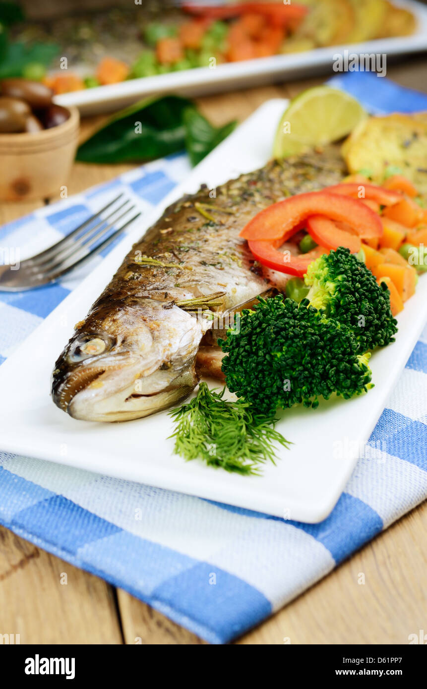 Dish with baked trout and vegetables on the kitchen table Stock Photo ...