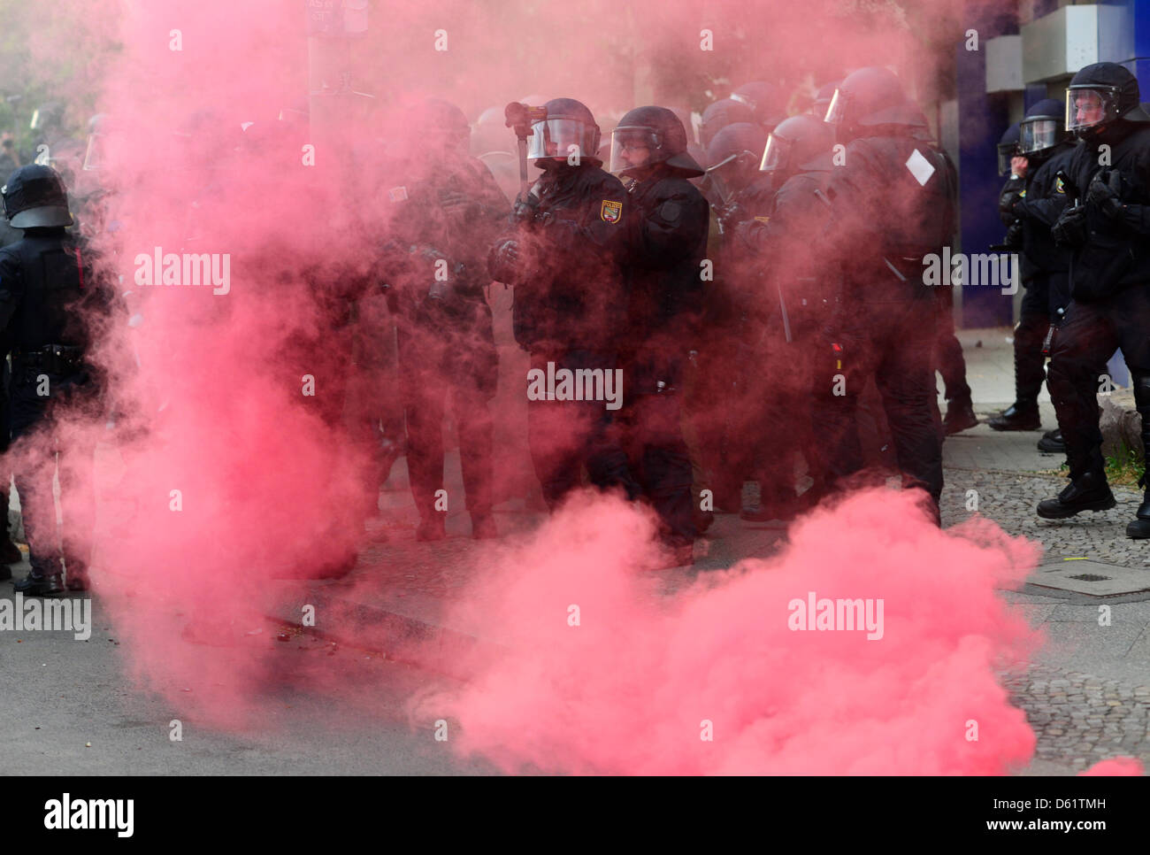 Police officers on riot gear stand in red smoke during a demonstration ...