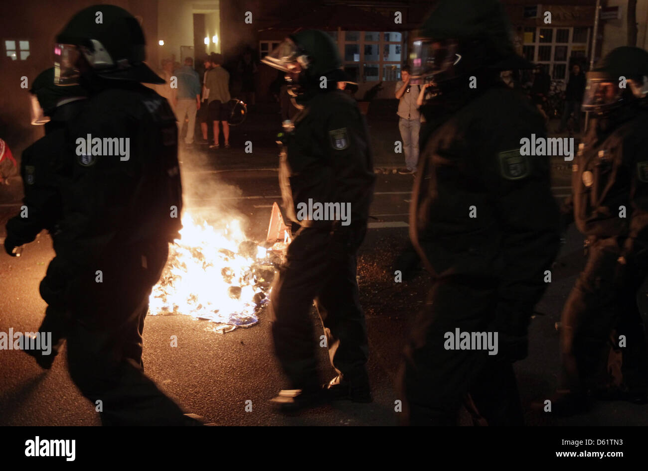 Police officers in riot gear walk past burning garbage cans during the ...