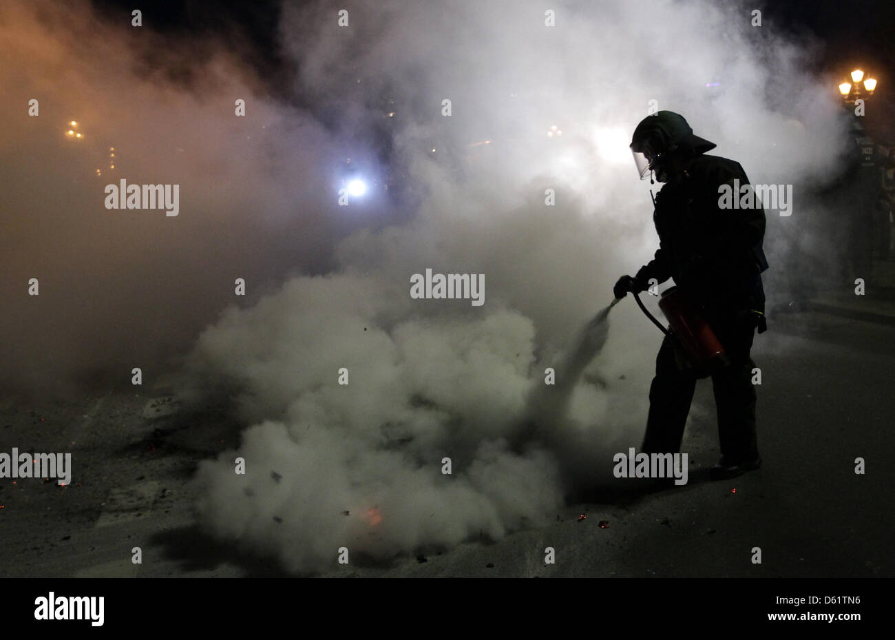 A police officer in riot gear extinguishes a burning garbage can during ...