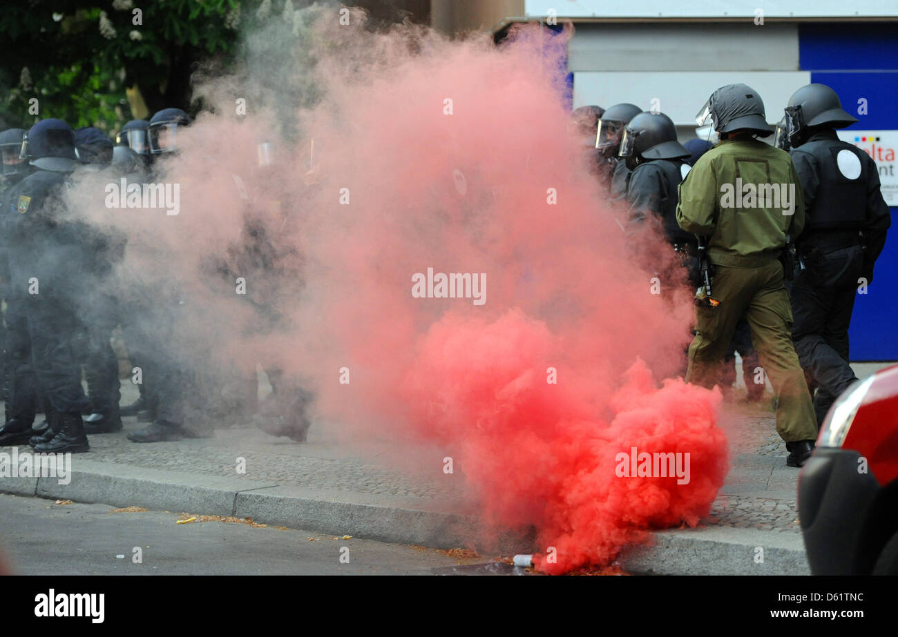 Police officers in riot gear walk past red smoke during the ...