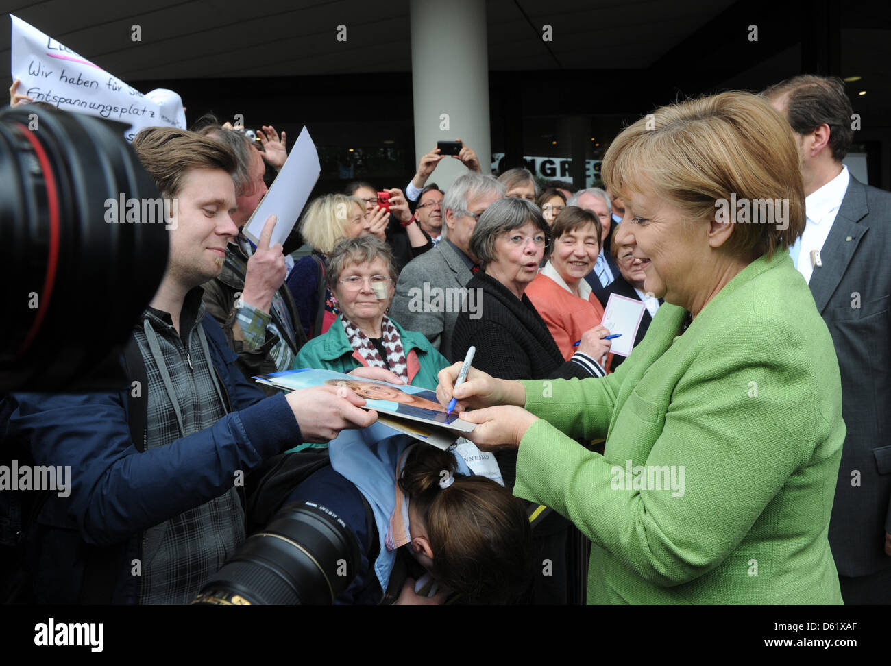 German Chancellor Angela Merkel (R) signs an autograph after her ...